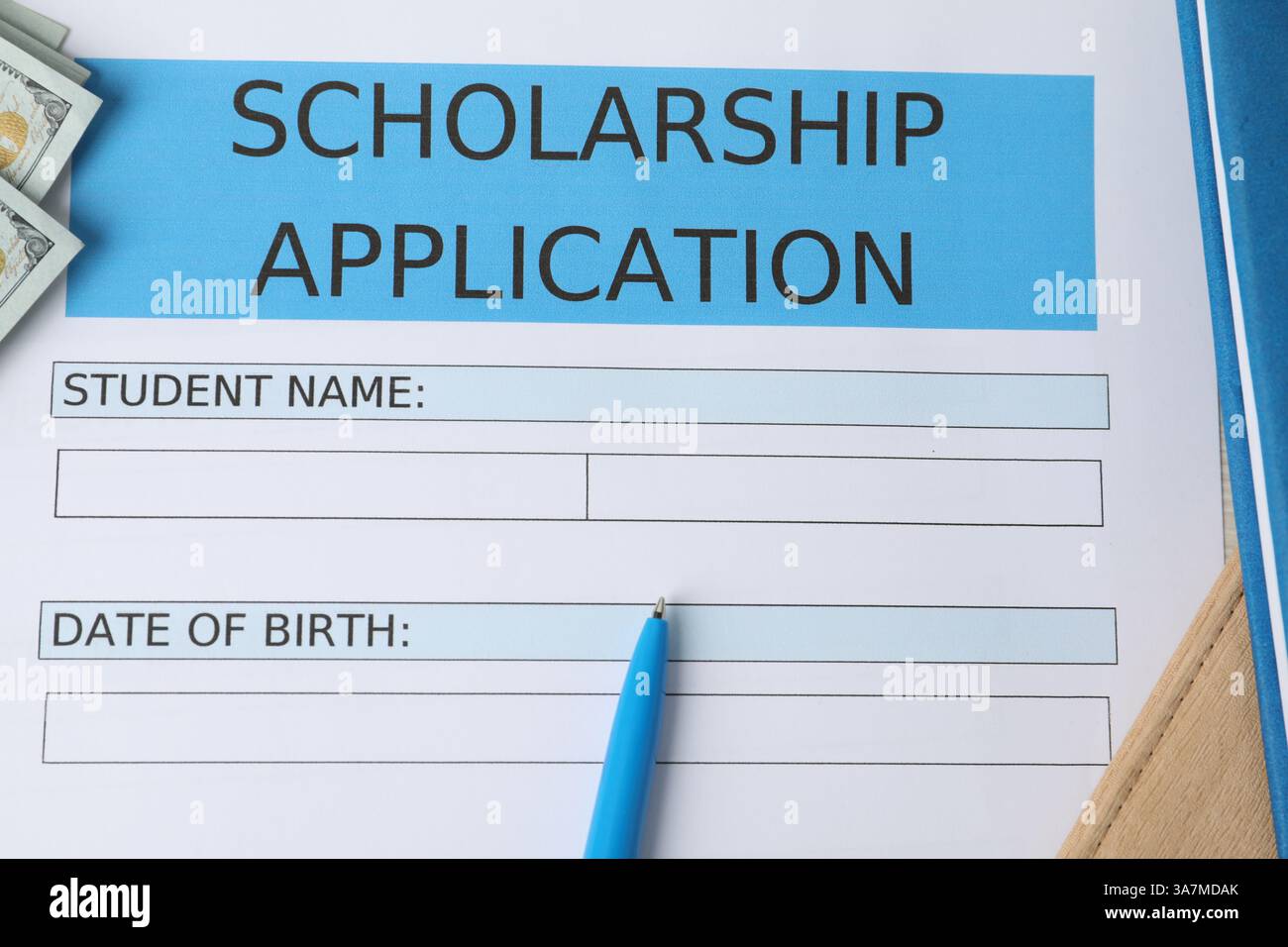 Scholarship application form, pen, dollar banknotes and book on table ...