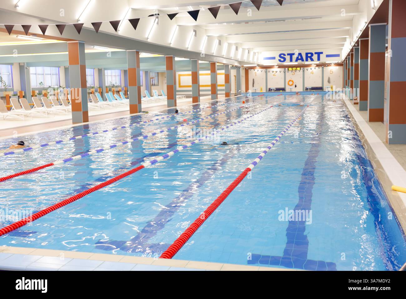 People swimming in indoor pool with clean water and lane dividers Stock ...