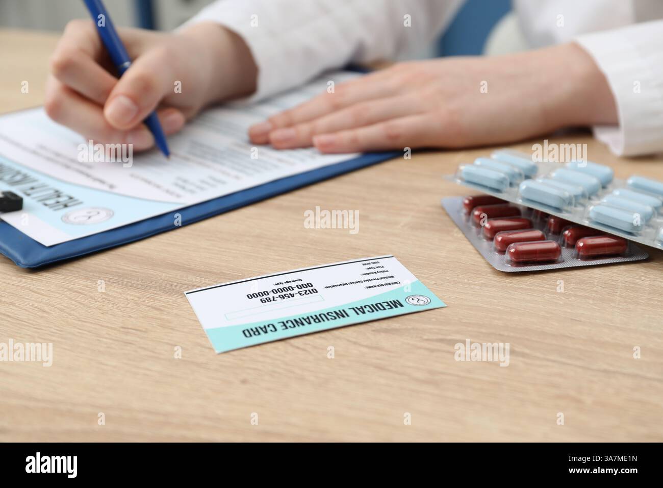 Doctor doing paperwork at wooden table, focus on health insurance card ...