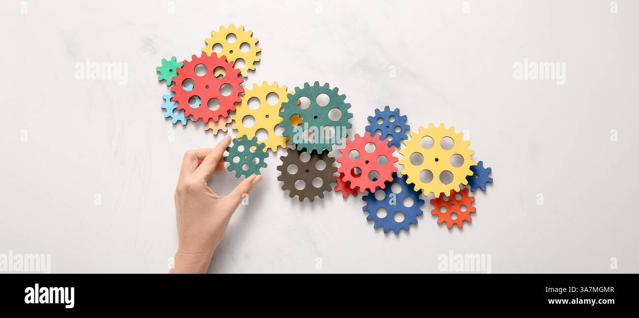 Hand with wooden gears on light background Stock Photo - Alamy