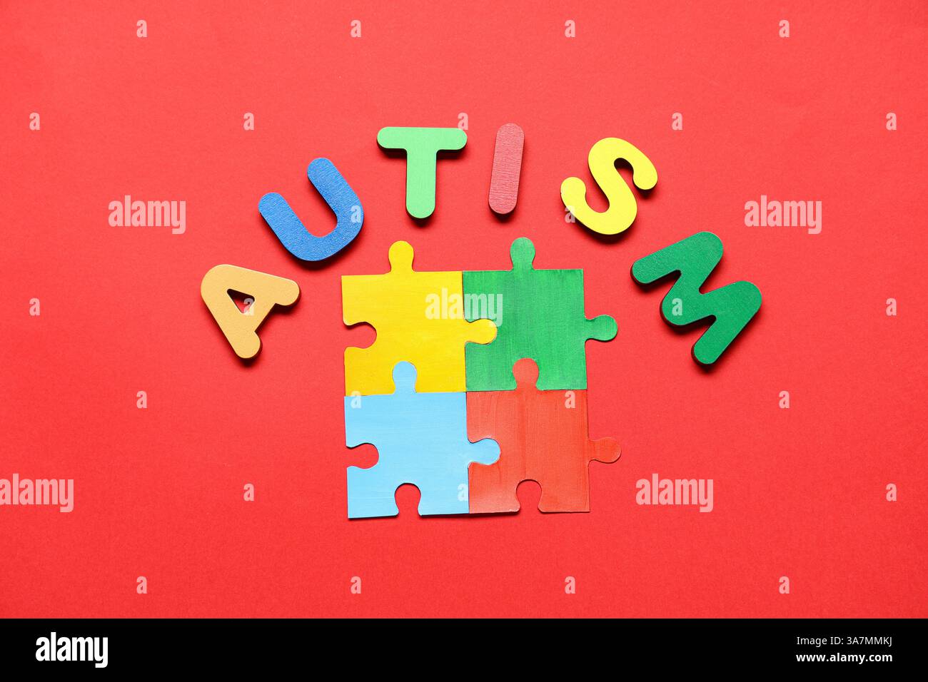 Word AUTISM with colorful puzzle pieces on red background. Autistic ...