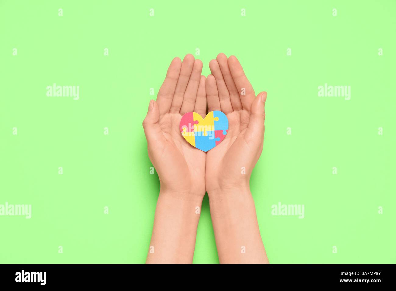 Female hands holding colorful puzzle pieces in shape of heart on green ...