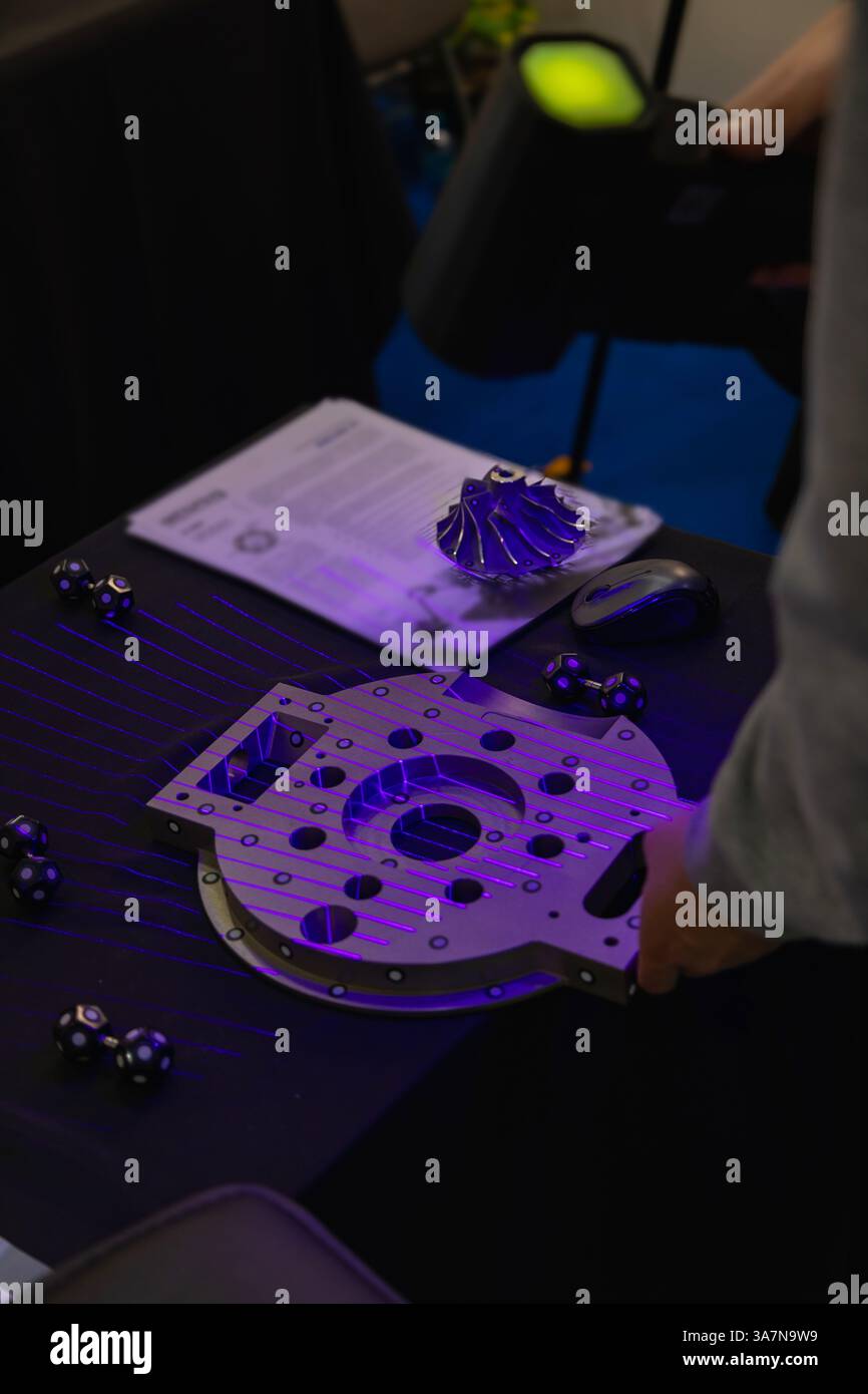 Mechanical engineer using a 3d scanner emitting purple laser beams to ...