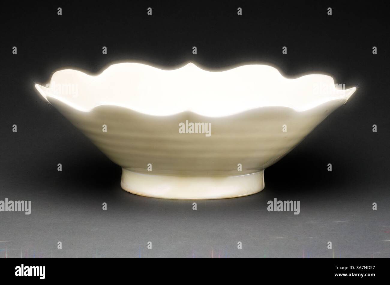 A delicately shaped serving bowl with a scalloped edge, featuring a ...