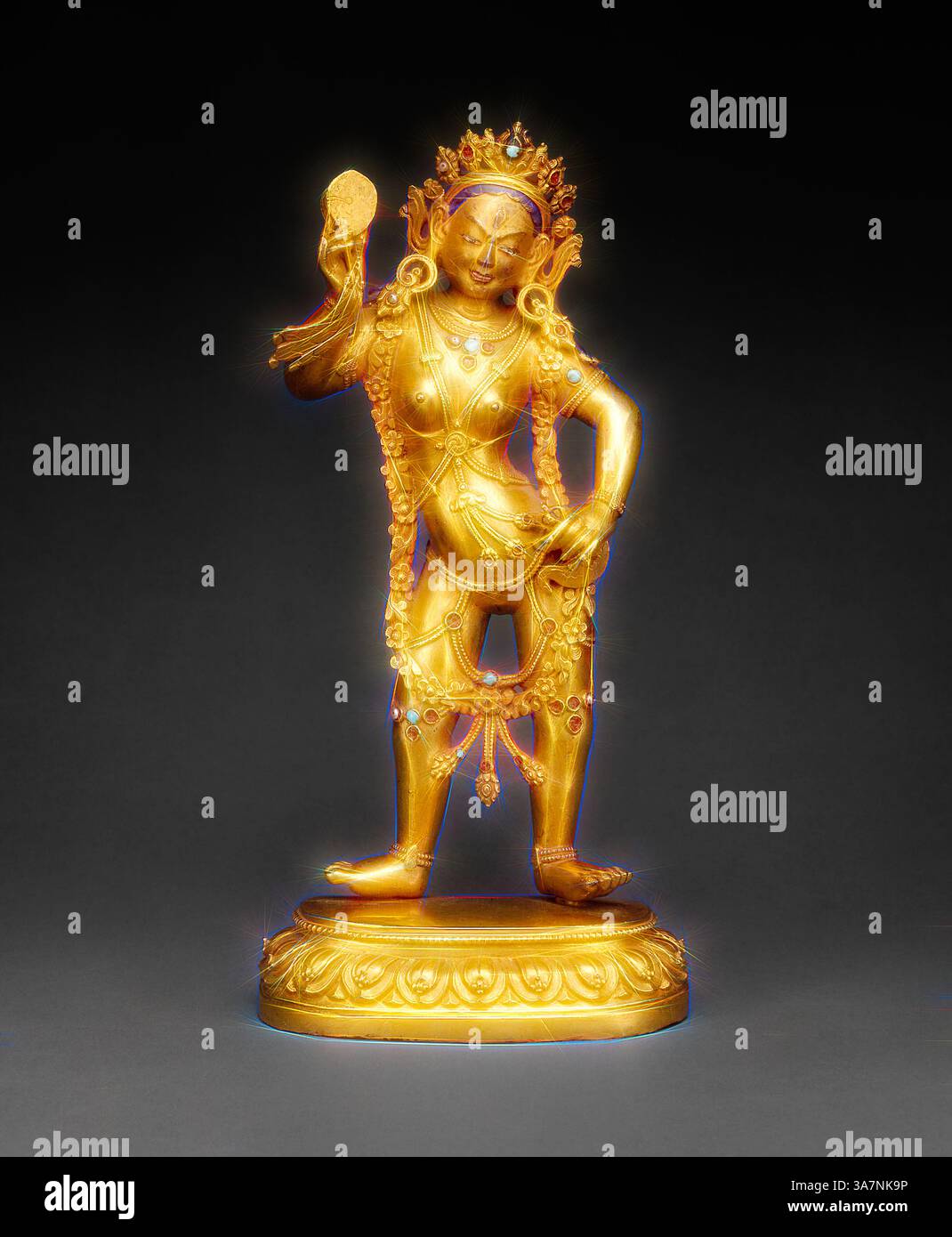 A golden statue of a deity stands confidently, one hand raised holding ...
