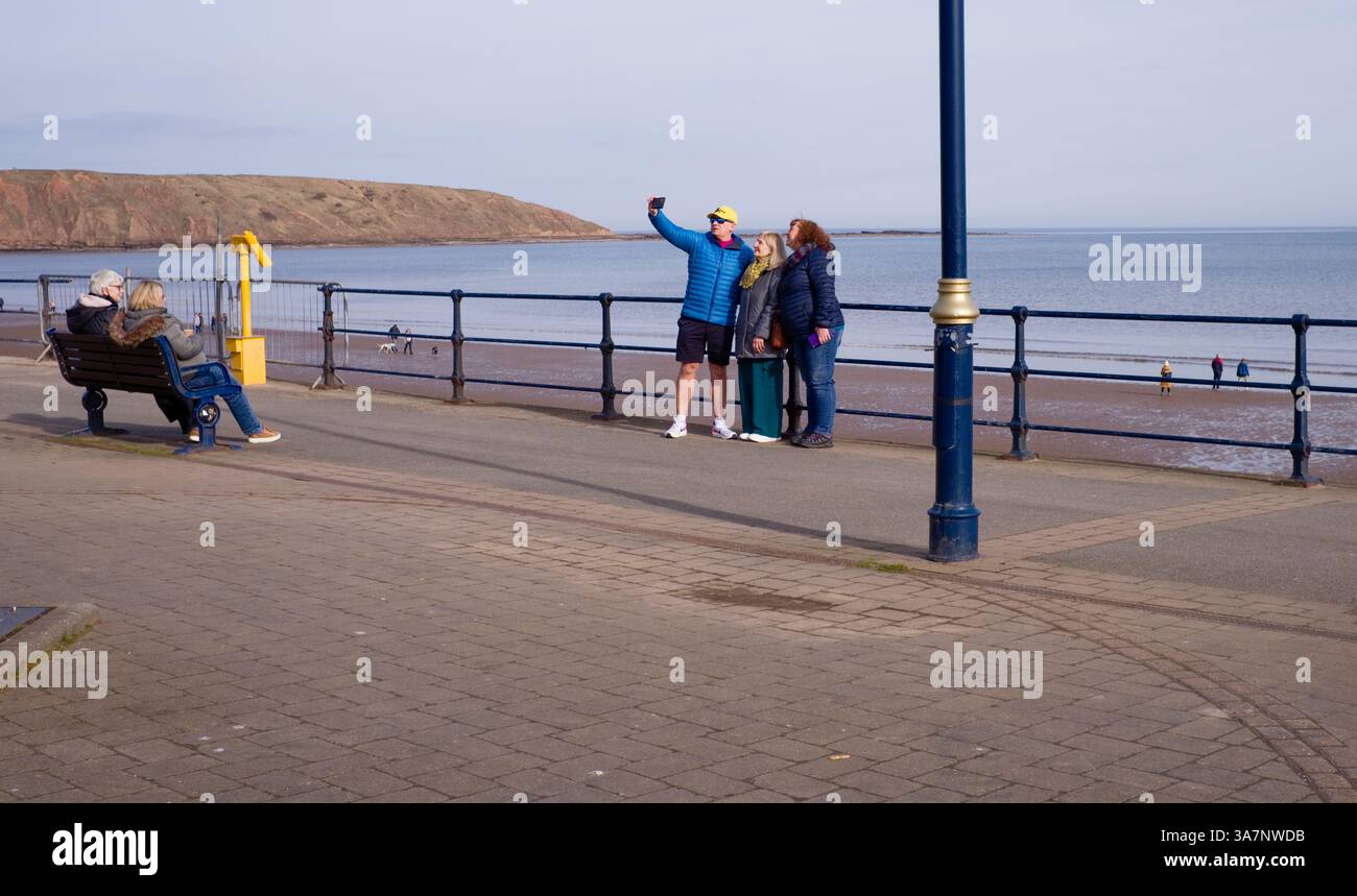 A group of three people taking a selfie on the prom at Filey Stock ...