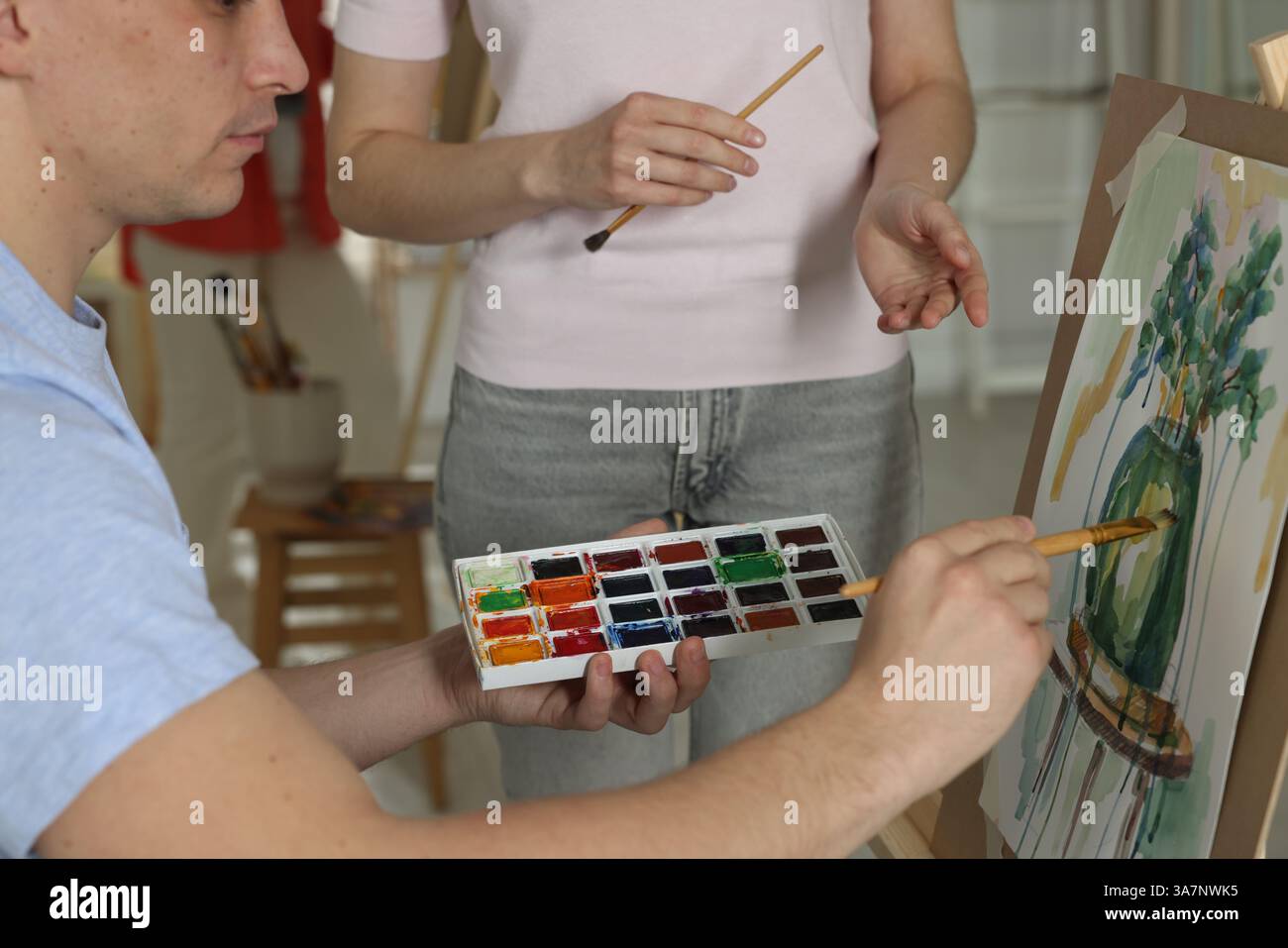 Artist teaching her student to paint in studio, closeup Stock Photo - Alamy