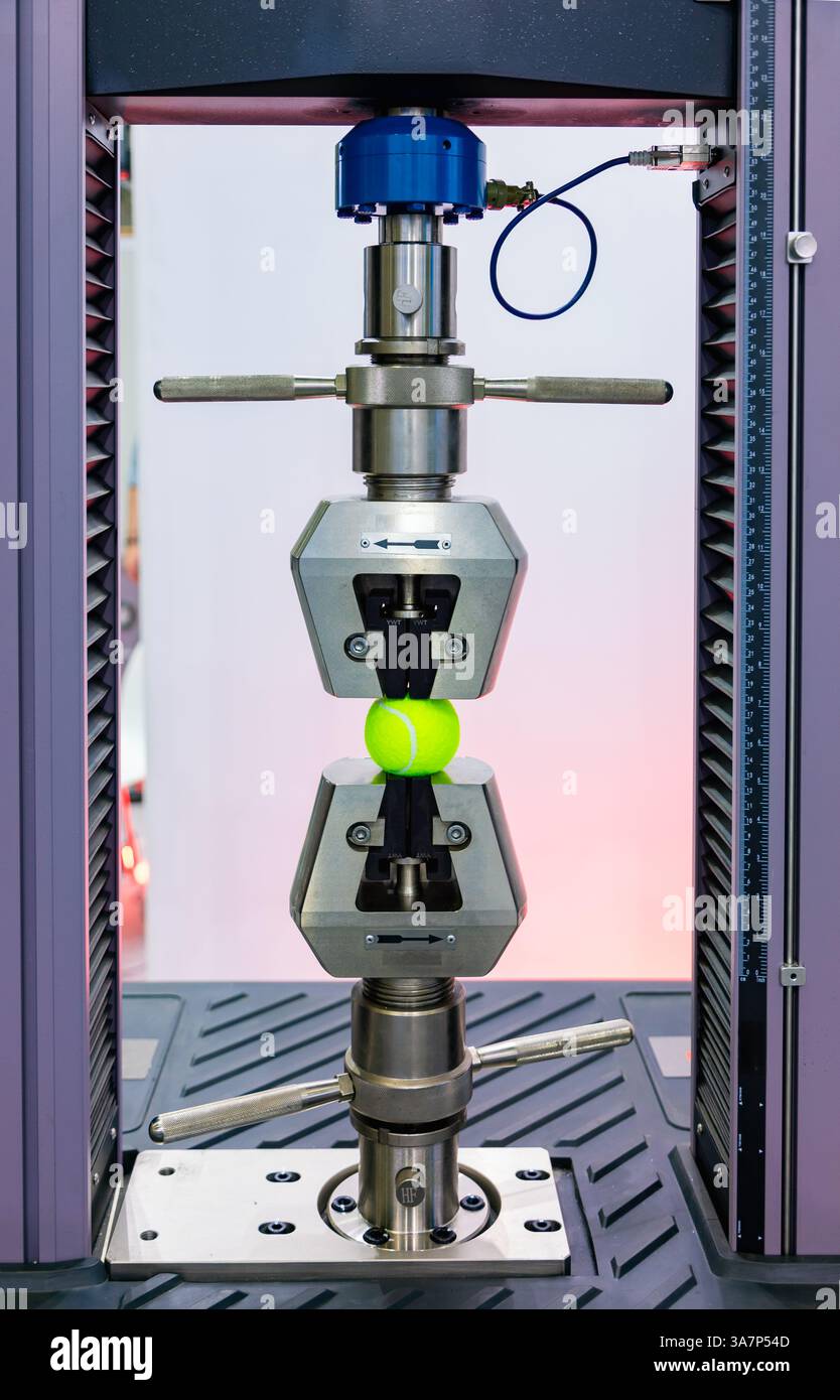 Material testing machine applying pressure on a tennis ball, performing ...