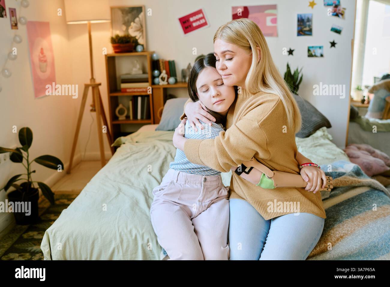 Loving mother gently hugging her daughter with prosthetic arm while ...