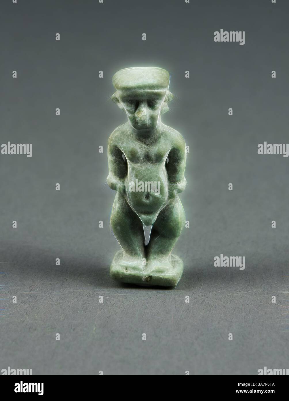 A small sculpted figure, likely carved from a smooth green stone ...