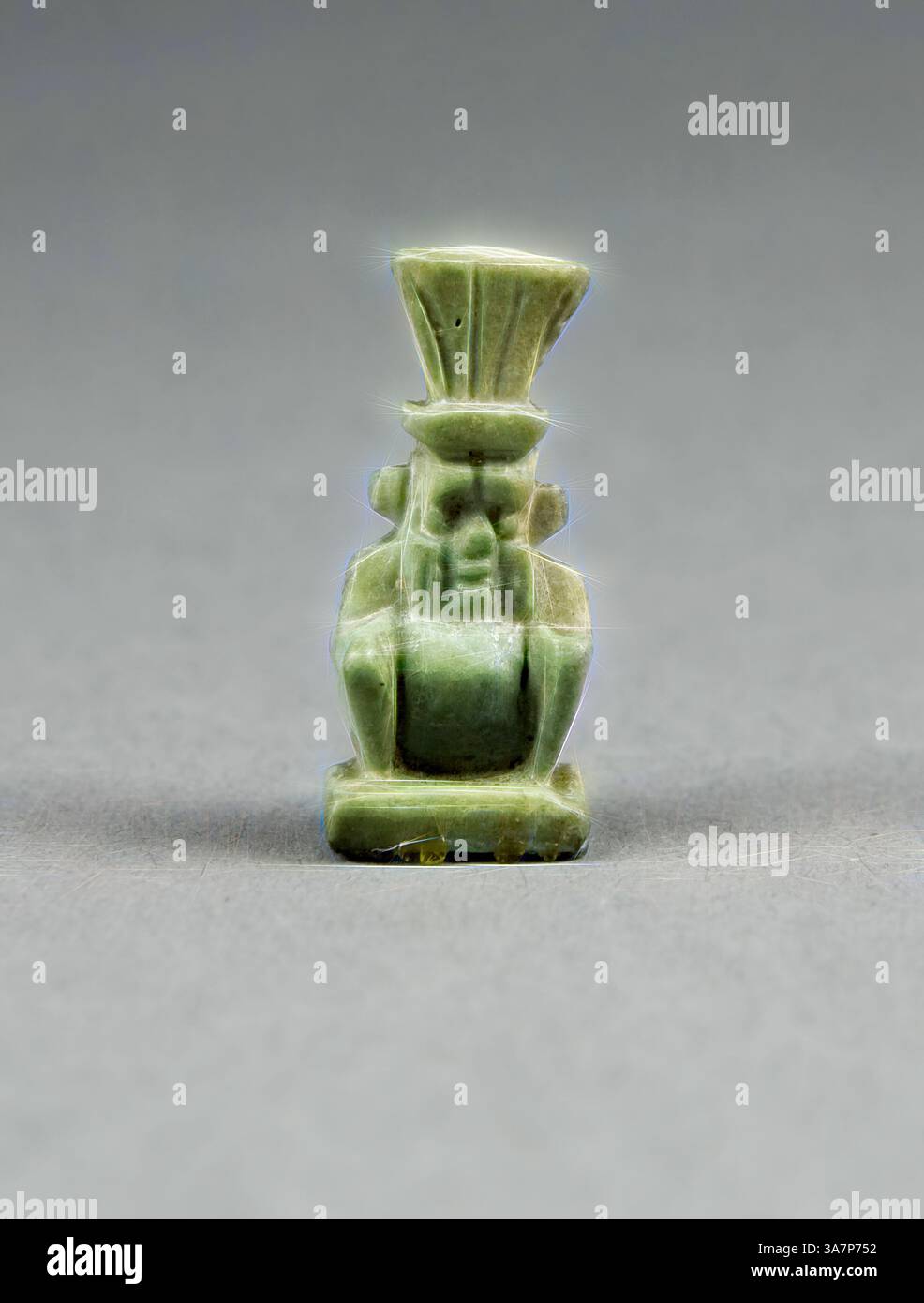 A small, intricately carved figure made of green stone, depicting a ...