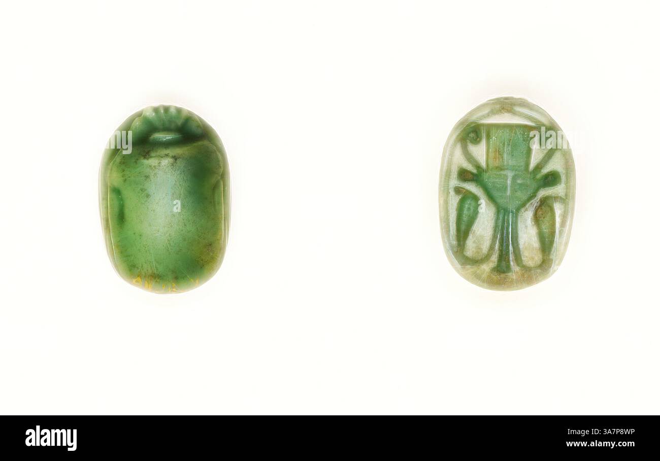 Two intricately carved scarab amulets made of stone, one in a deep ...