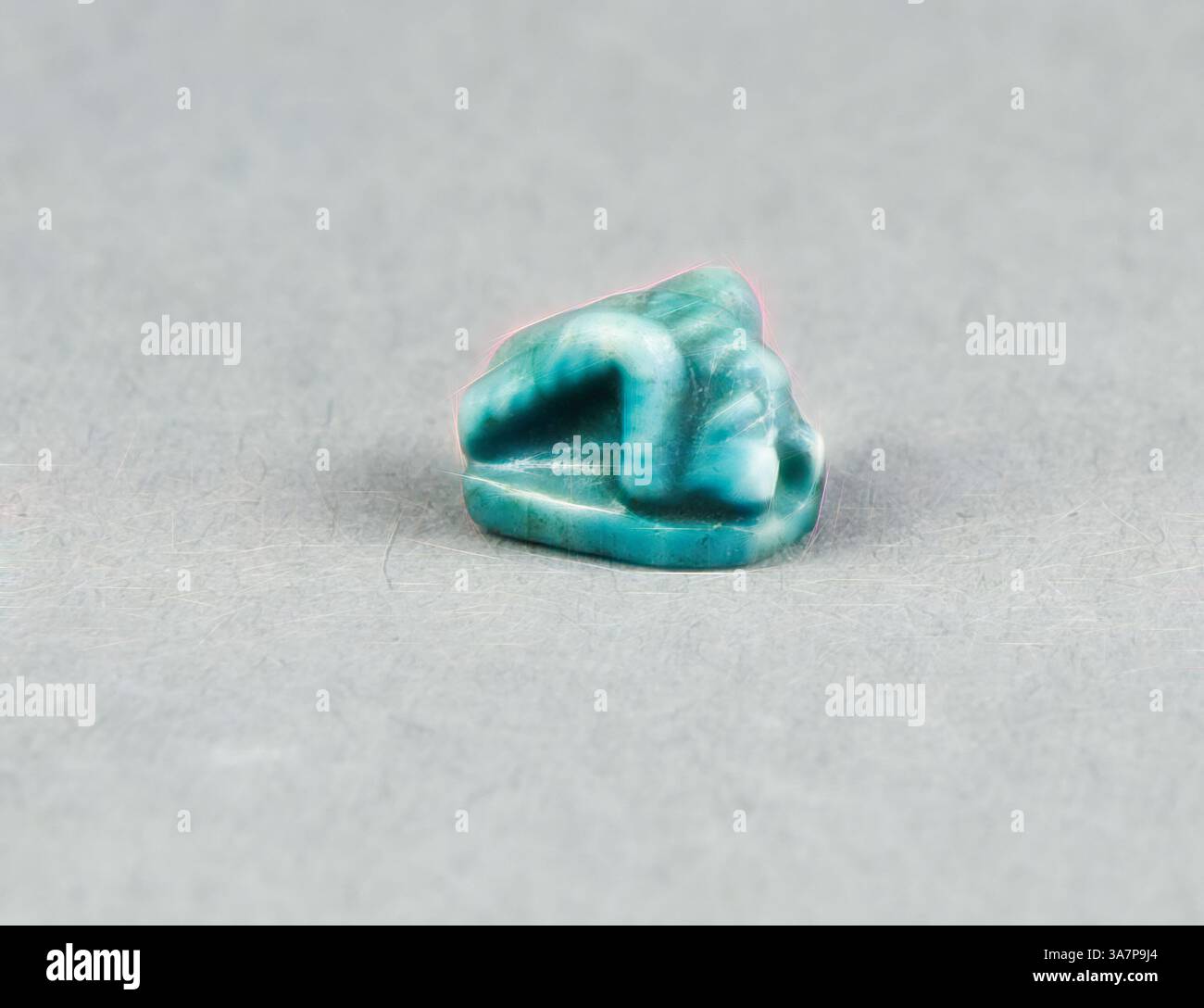 A small, intricately shaped stone with a smooth surface and a vibrant ...