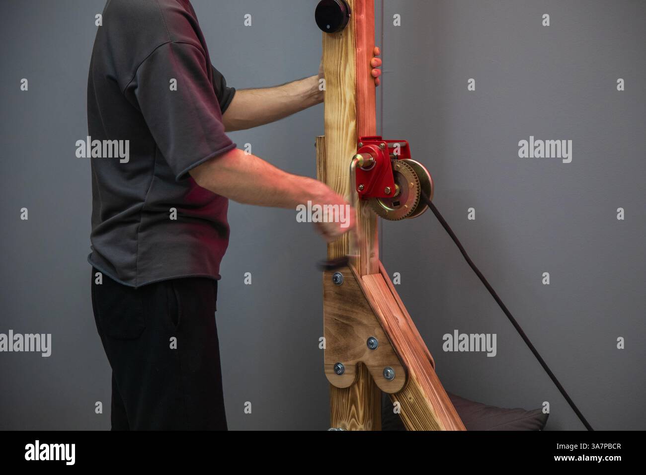 Technician operates a hand winch attached to a wooden structure ...