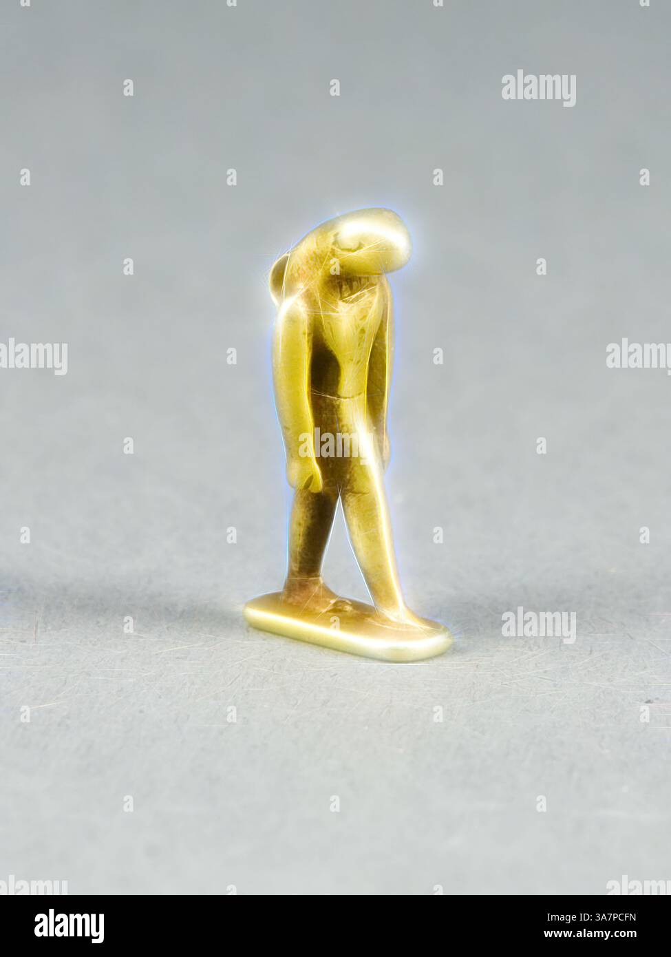 A small, intricately carved figure stands in a relaxed posture, with ...
