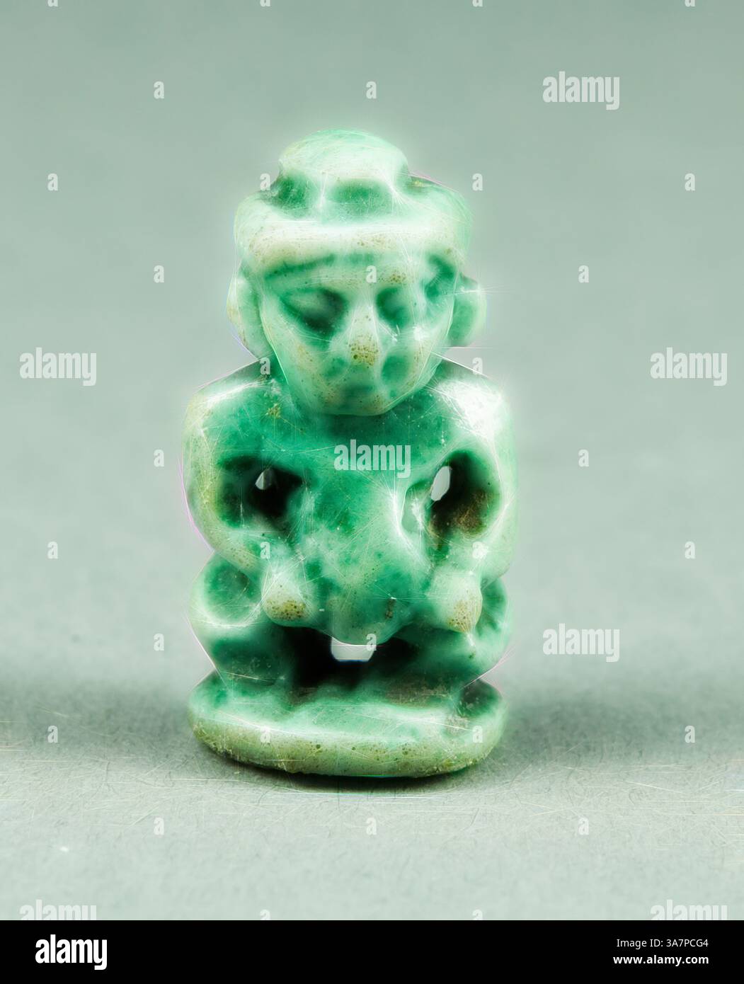 A small, intricately carved jade figure depicting a seated figure ...