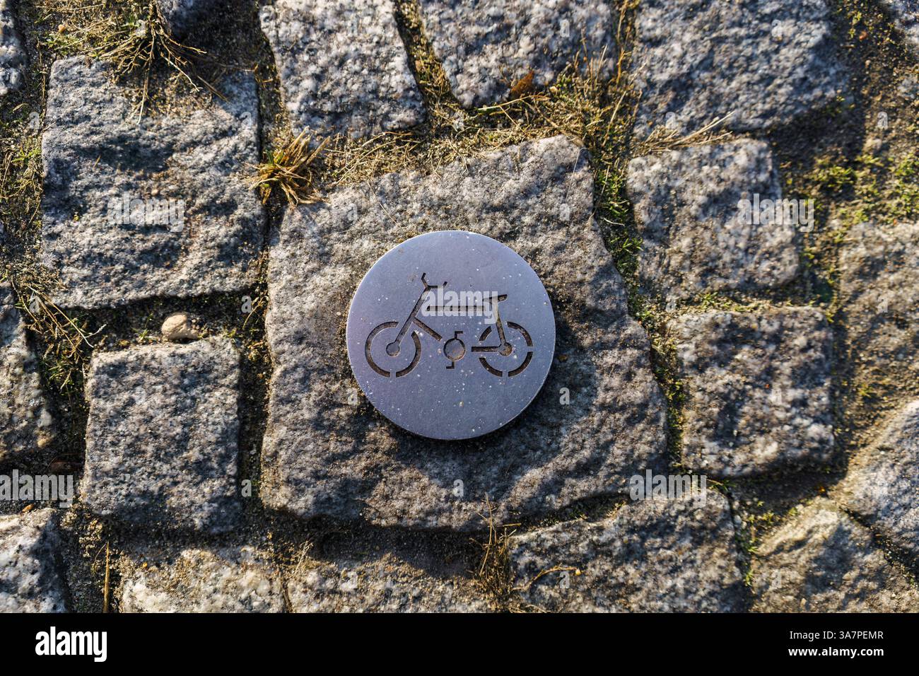 Metal bicycle symbol embedded in cobblestone pavement Stock Photo - Alamy