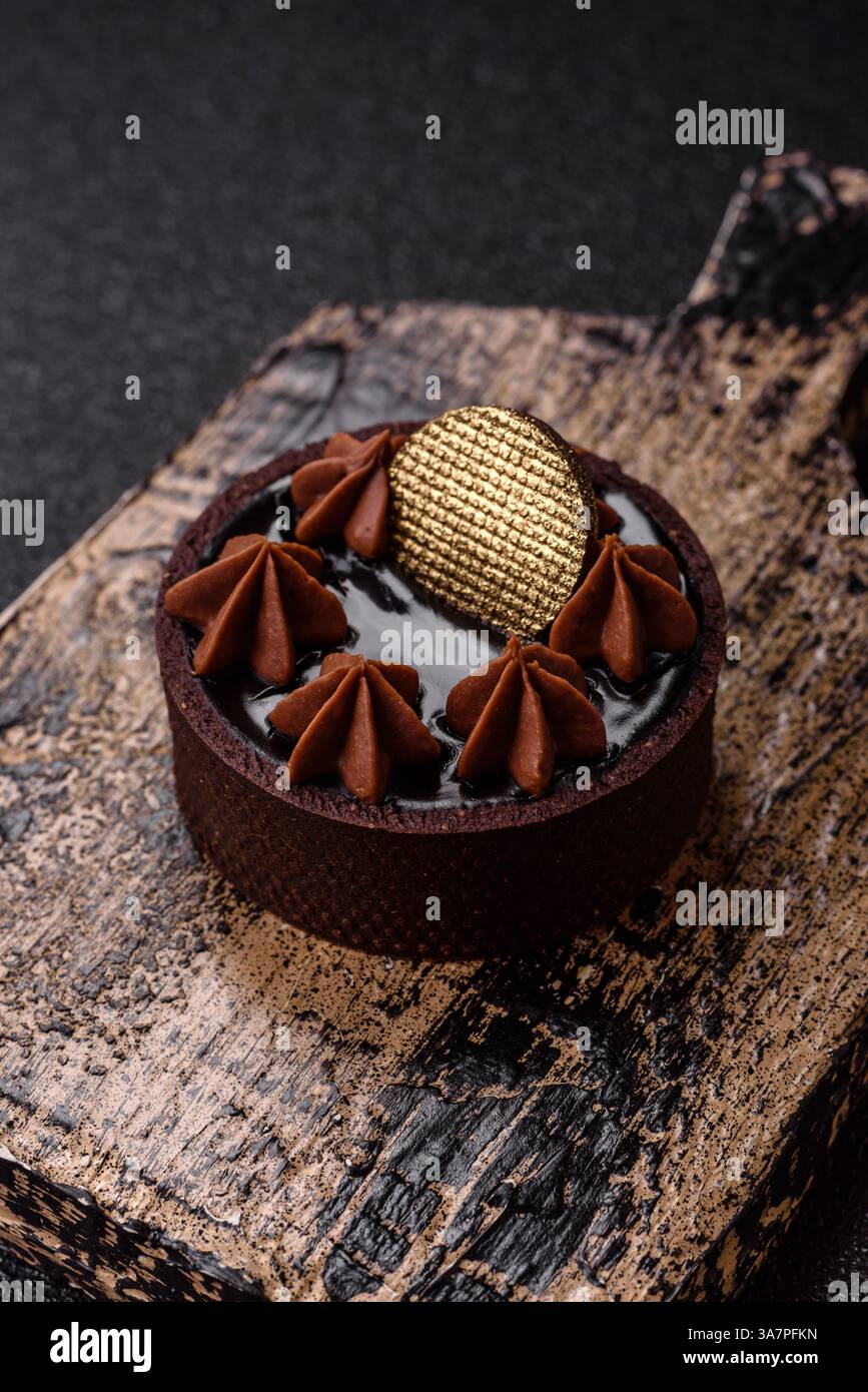 Sweet round tart with chocolate coating and nut filling on dark ...