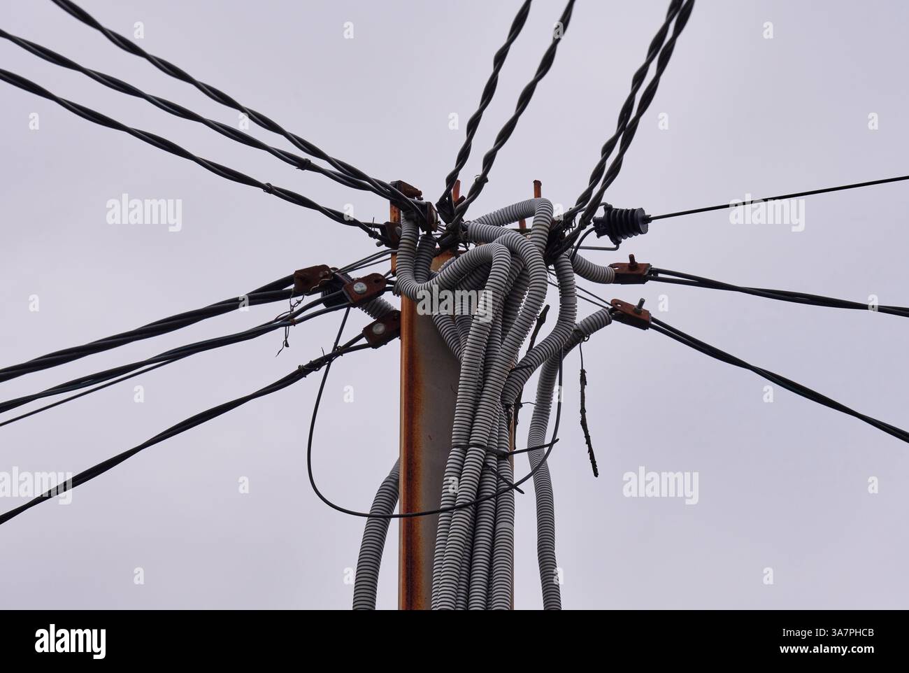 Electrical pole with numerous tangled cables and wires. The ...