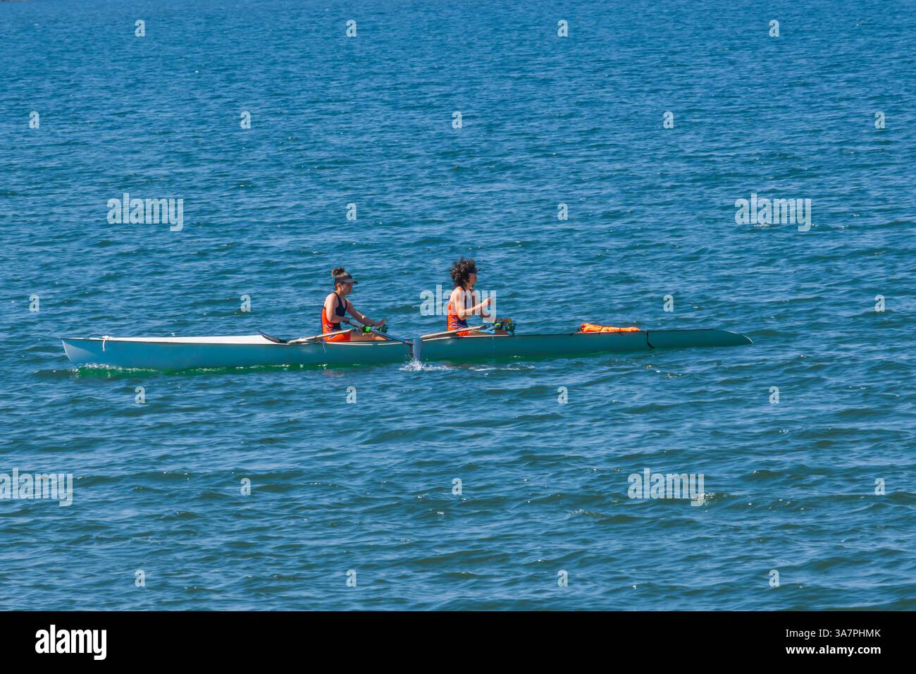Two rowers glide through the ocean in perfect sync, their boat cutting ...