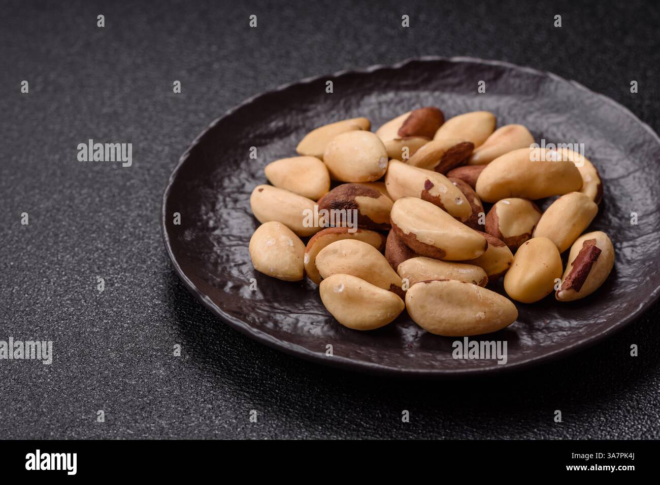 Brazil nut kernels in ceramic bowl on dark concrete background Stock ...