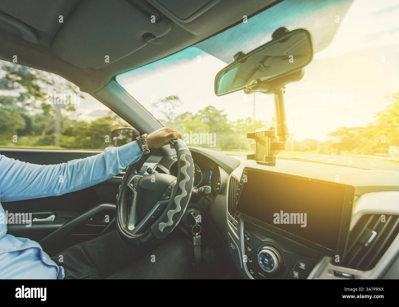 Interior view of a man driving a car. Driver hands on the steering ...