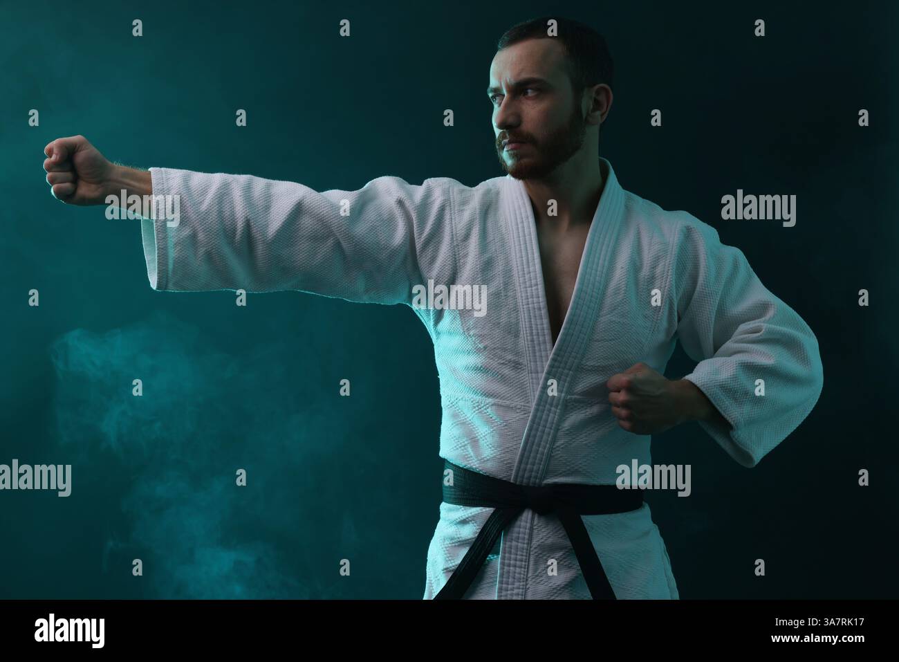 Man wearing uniform practicing karate in color lights and smoke Stock ...