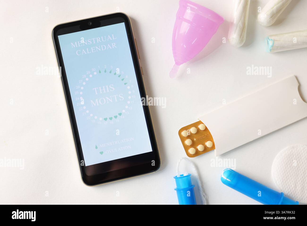 Smartphone with period calendar application and menstrual products on white table, flat lay ...
