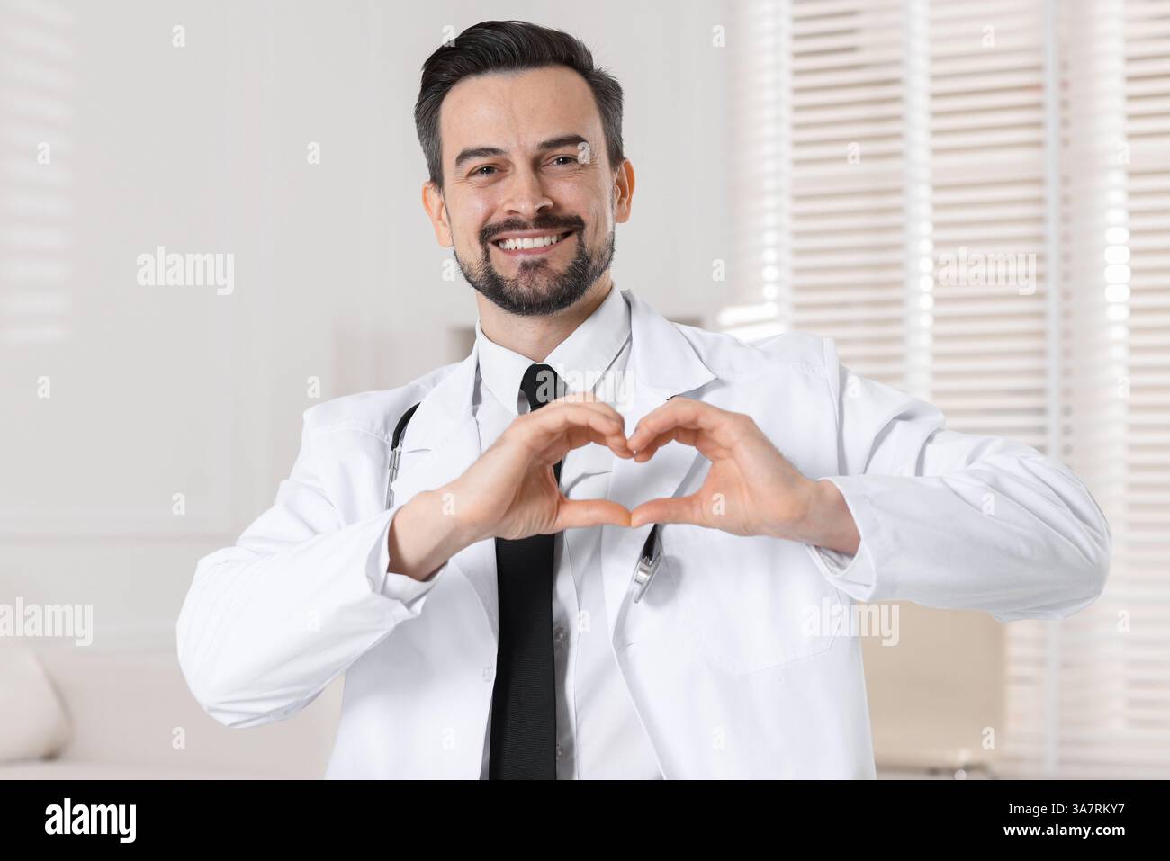 Smiling cardiologist making heart with hands indoors Stock Photo - Alamy
