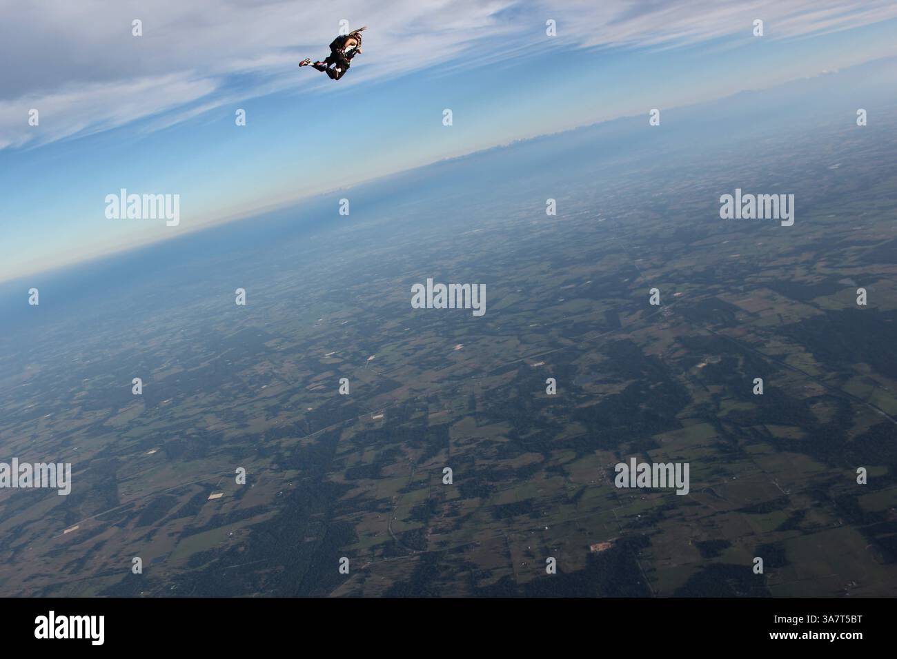 Tandem skydivers floating with parachute against blue sky over Texas ...