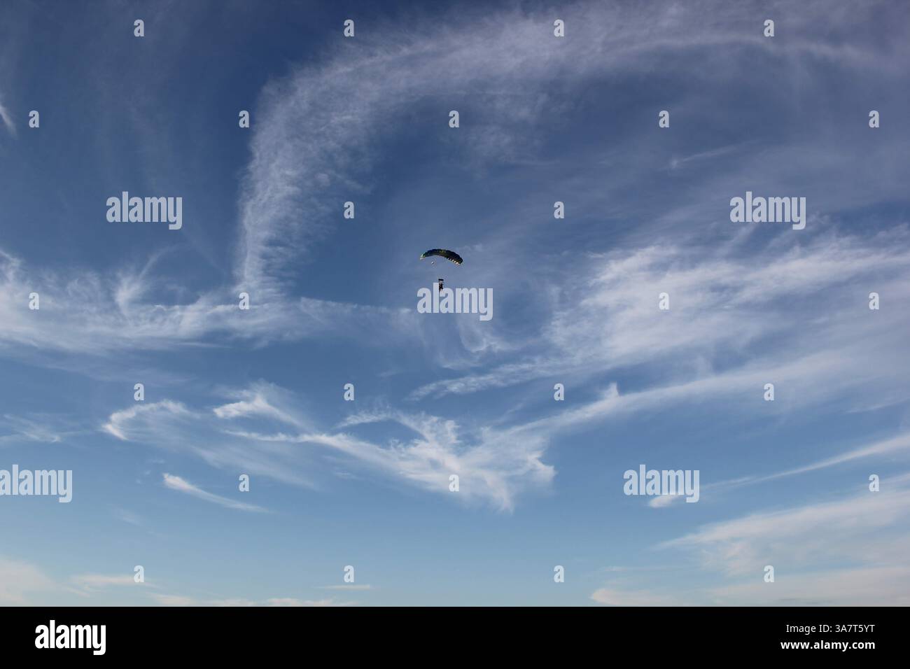 Tandem skydivers floating with parachute against blue sky over Texas ...