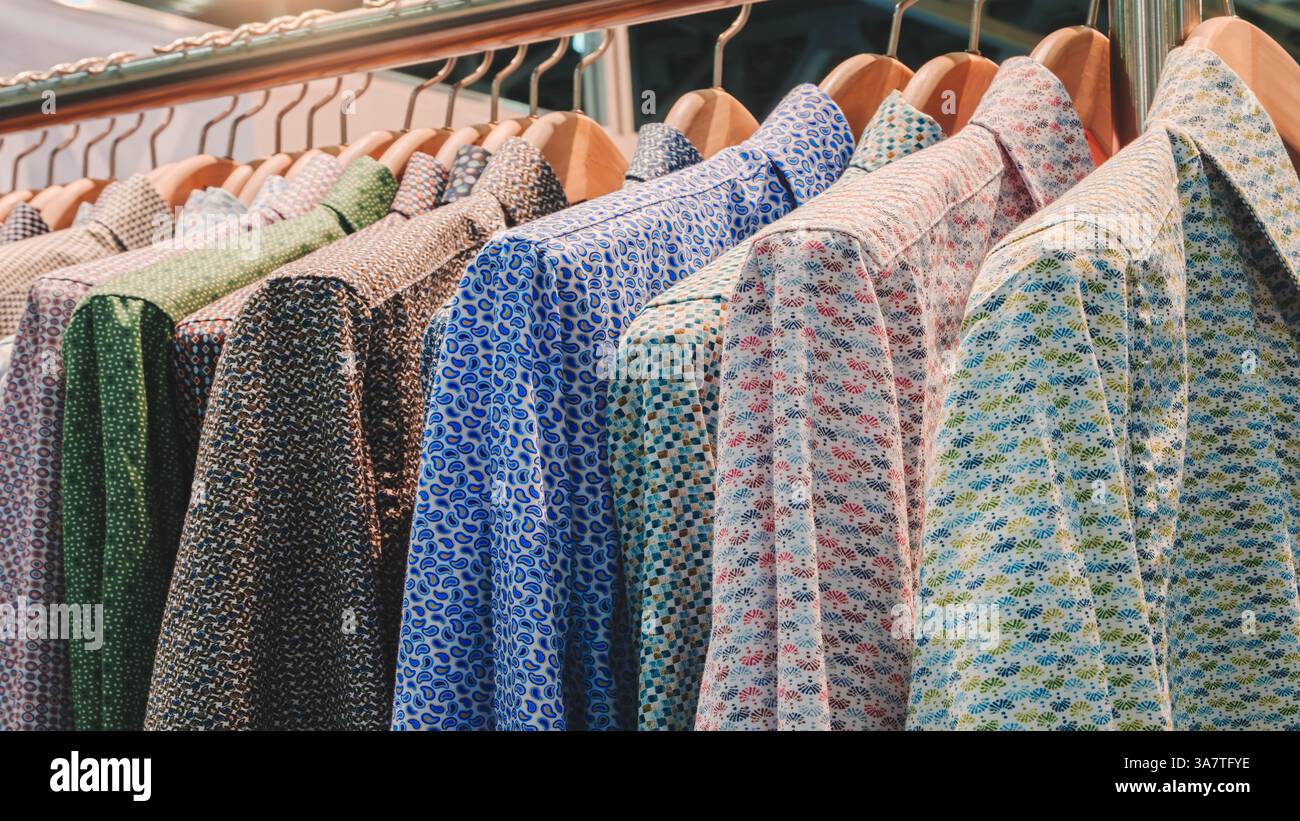 A rack of clothes with a variety of colors and patterns, including ...
