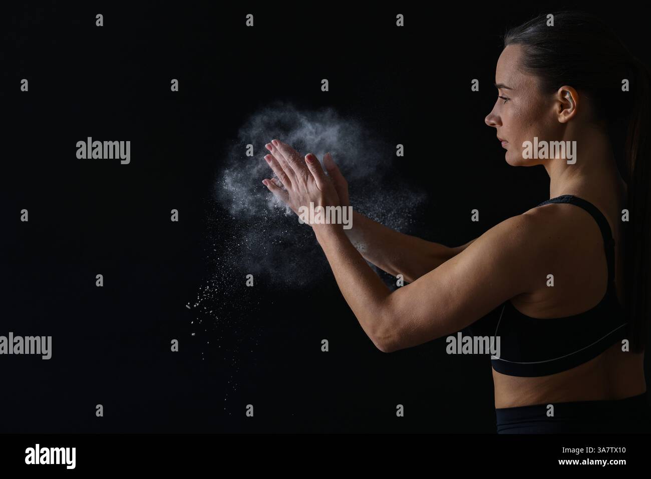 Woman clapping hands with talcum powder before training on black ...