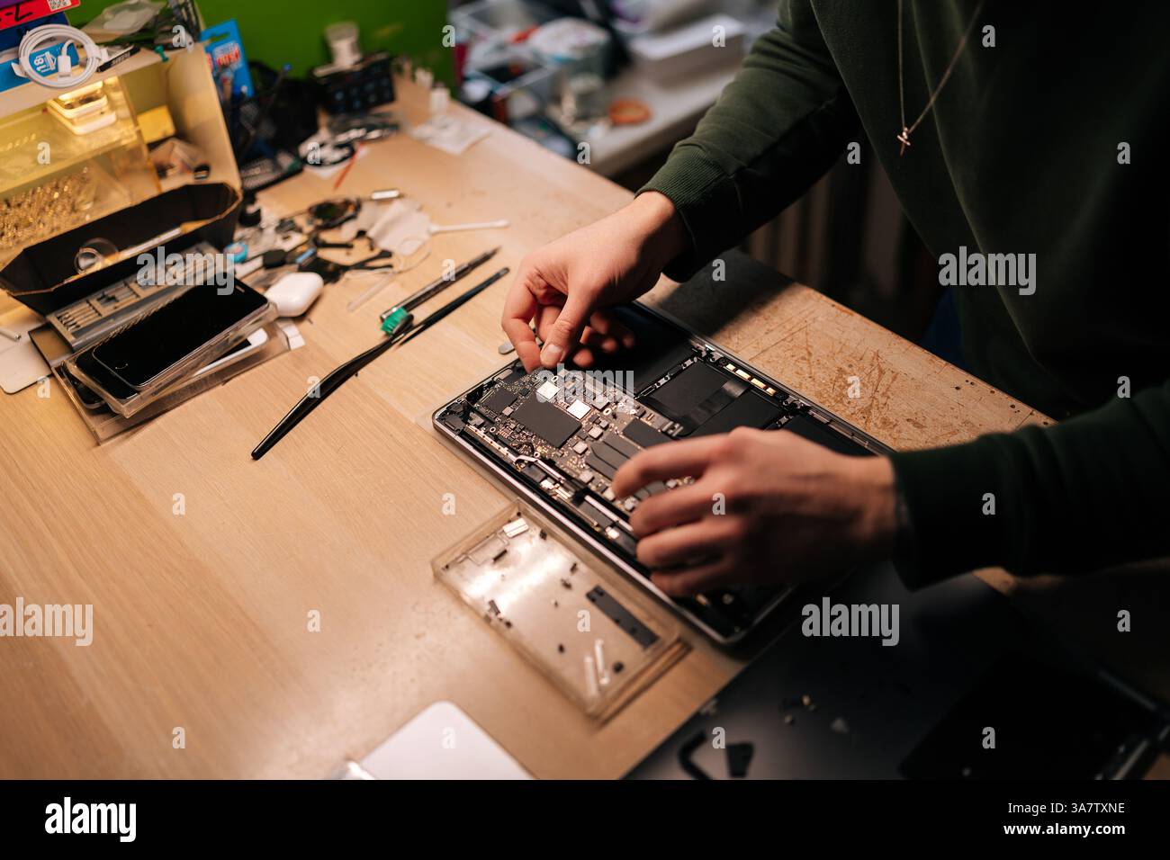 Top view of technician using tweezers repairing delicate laptop motherboard components in ...