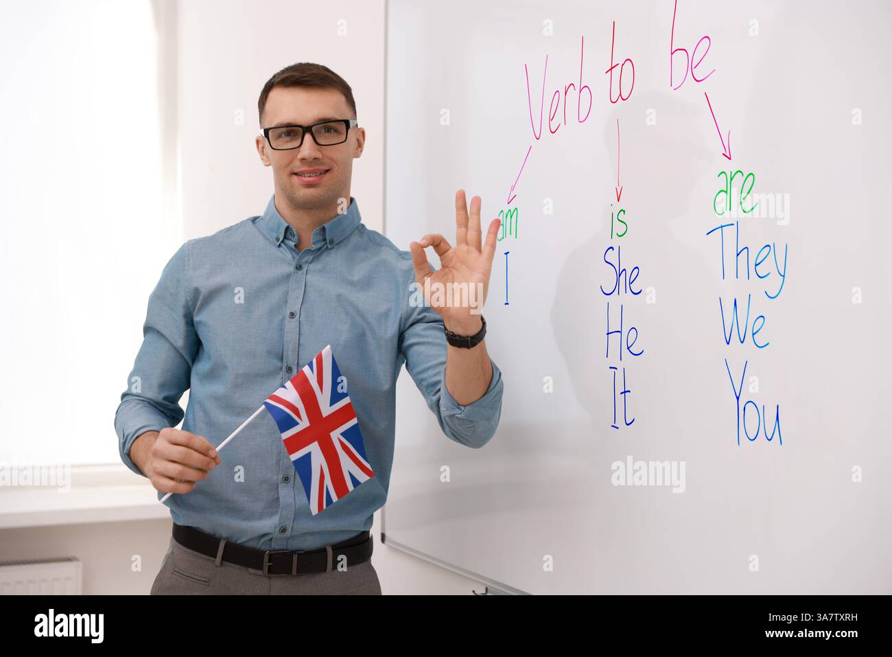 English teacher with UK flag showing OK gesture near whiteboard in ...