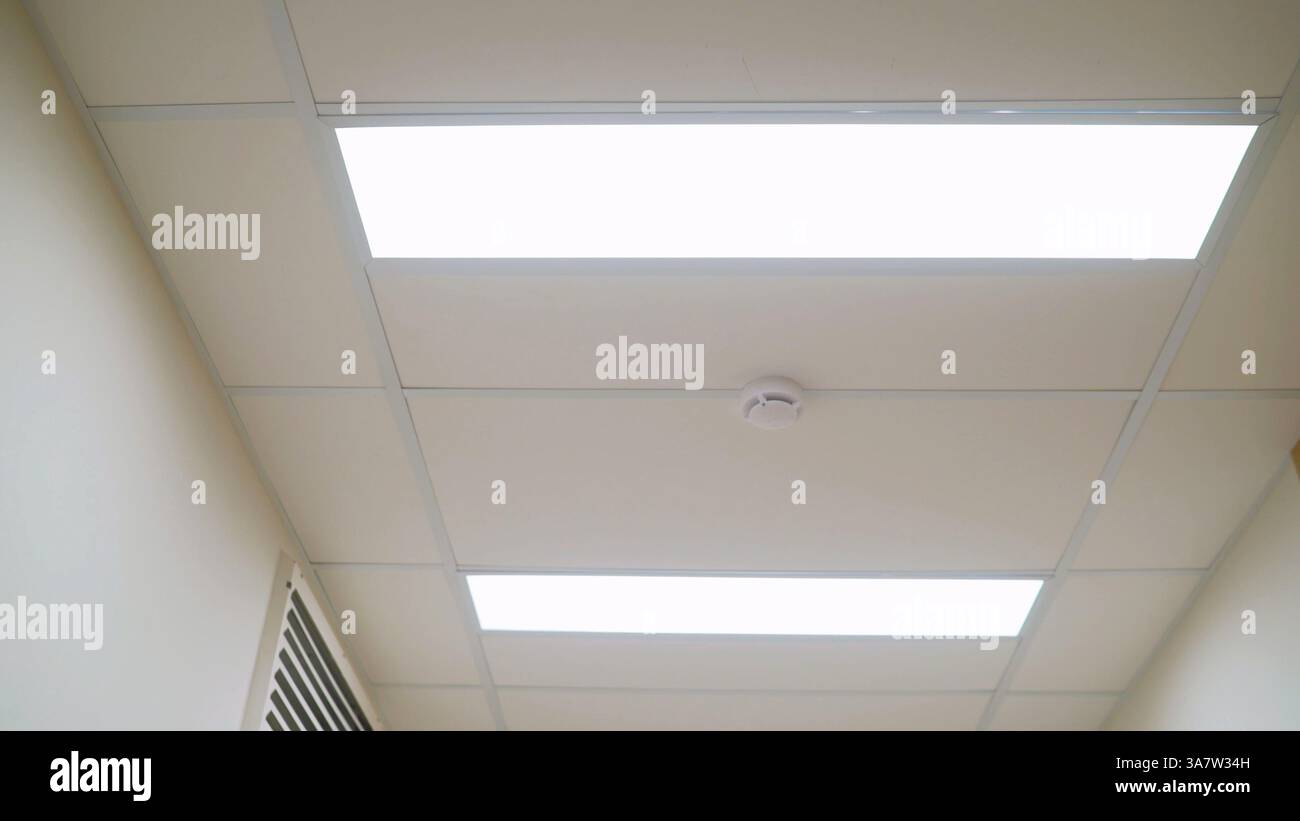 Office ceiling with integrated led panel lights and a smoke detector ...