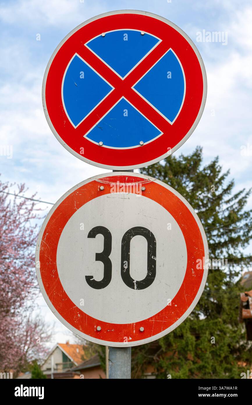 Two traffic signs are displayed on a pole in a residential area, with ...