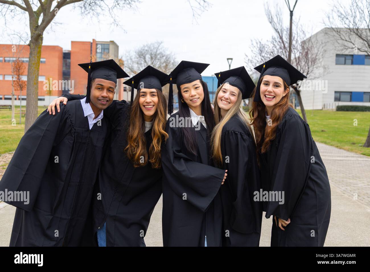 Multiethnic group of students wearing graduation gowns and caps ...