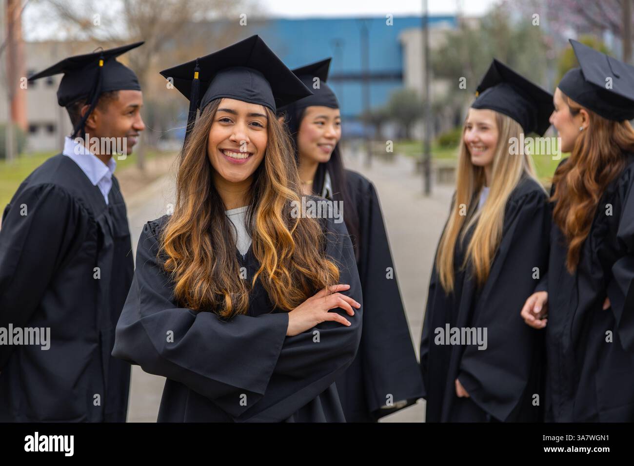 Portrait of cheerful graduate student smiling with arms crossed while ...