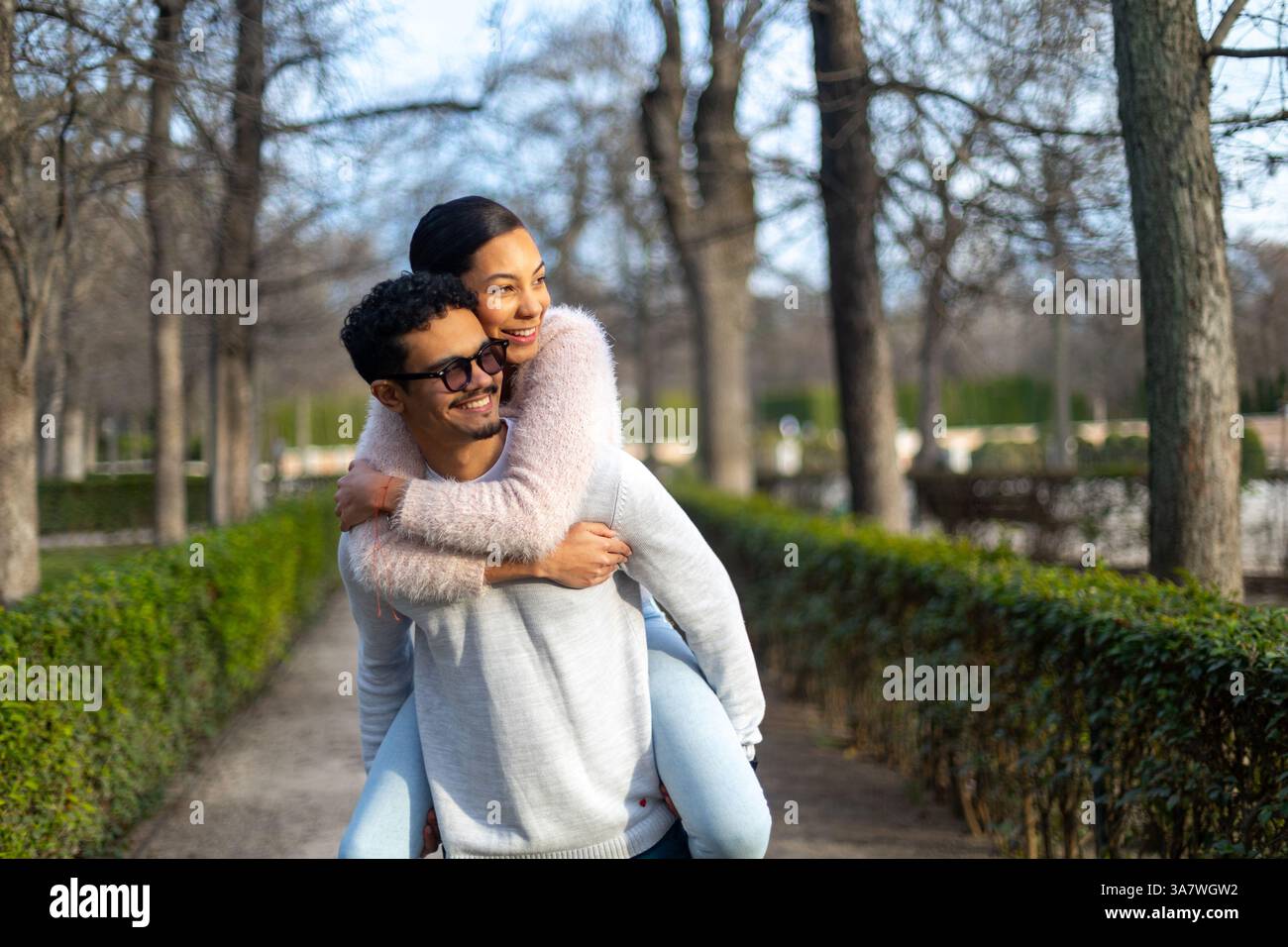 Young man giving piggyback ride to his girlfriend while walking in a ...
