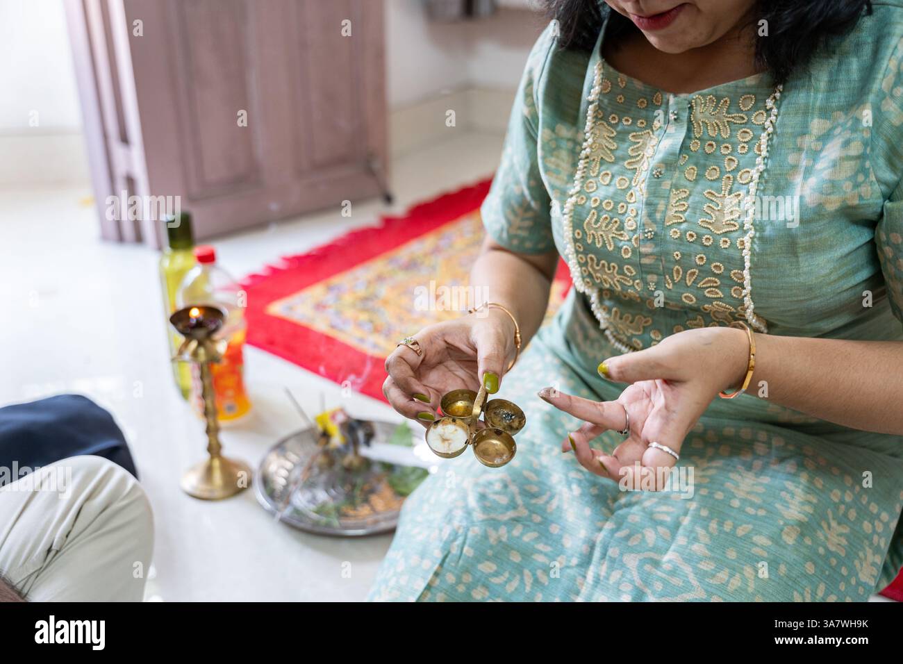 Indian woman preparing small oil lamps for a puja ritual in a home ...