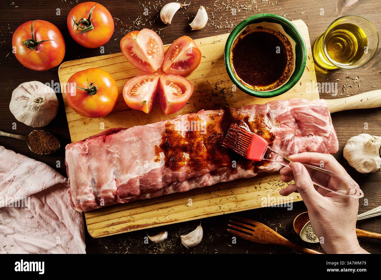 From above of crop anonymous chef spreading barbecue sauce on raw pork ...
