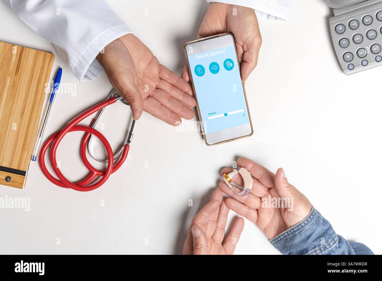 Doctor showing mobile application to adjust patient's hearing aids ...