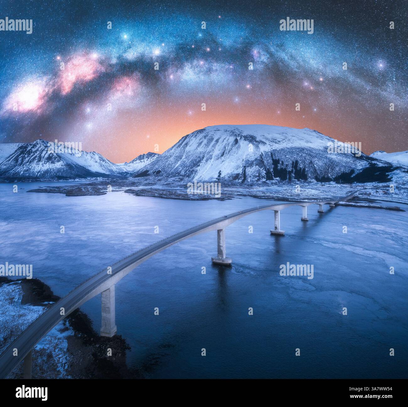 Aerial view of Milky Way arch over beautiful bridge, fjord and snowy ...