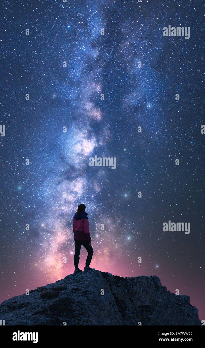 Glowing Milky Way and woman on mountain peak at starry night. Dolomites ...