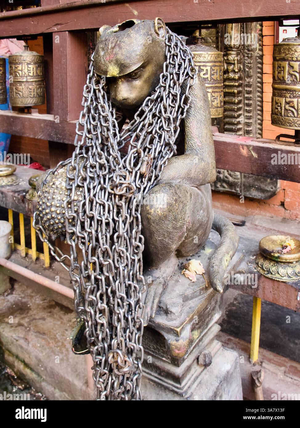 Monkey statue holding jackfruit offering, draped in chains at the 12th ...