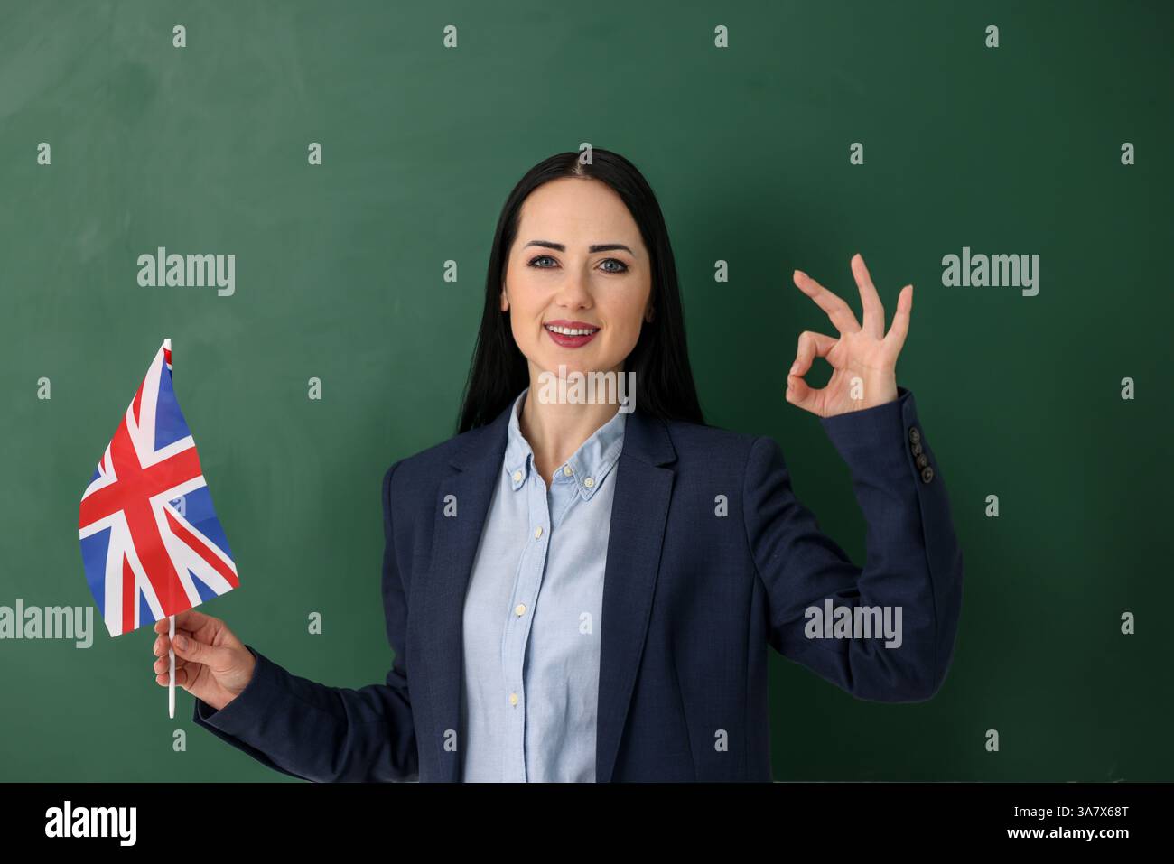 English teacher with UK flag showing ok gesture near chalkboard in ...