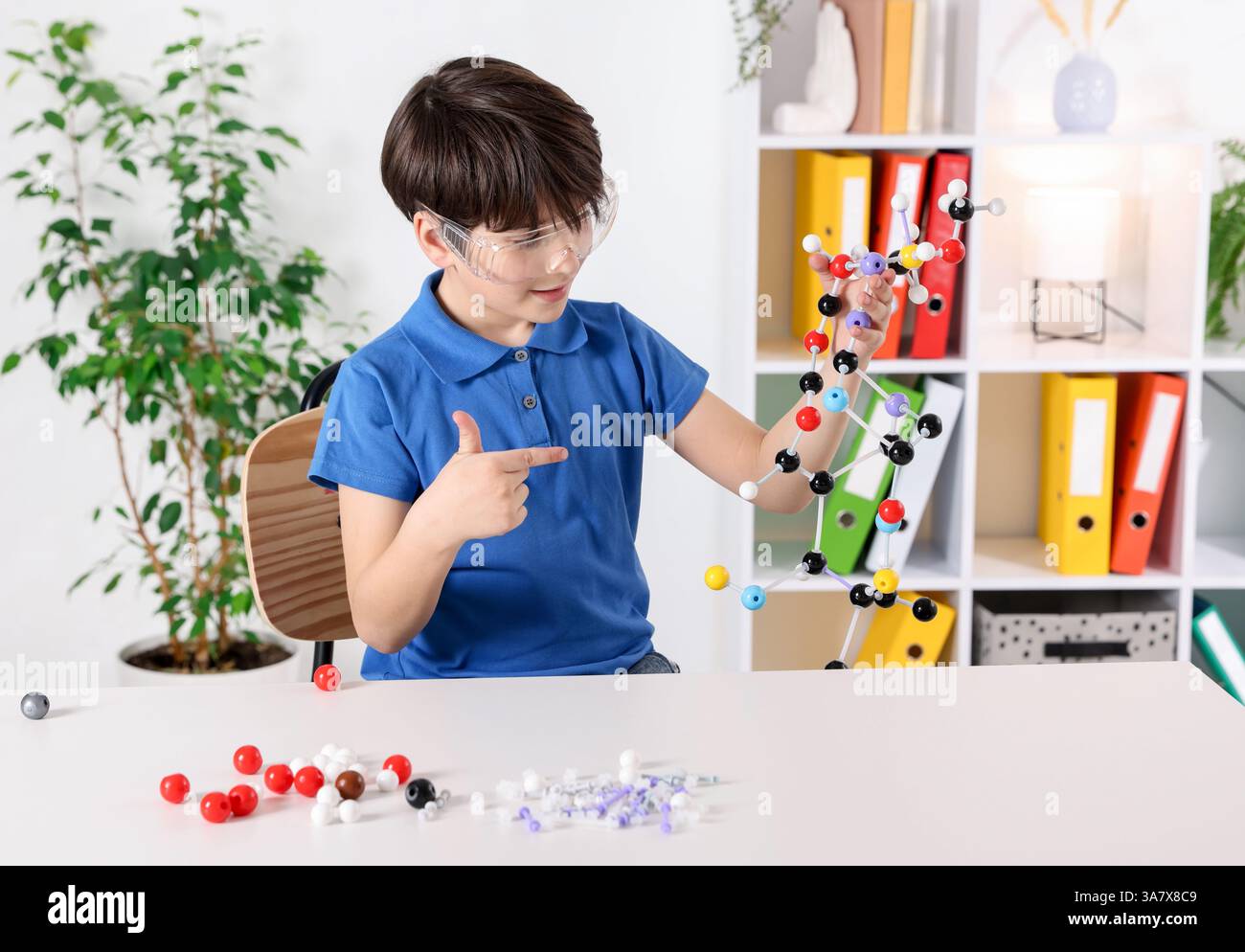 Boy showing DNA structure model at desk indoors Stock Photo - Alamy