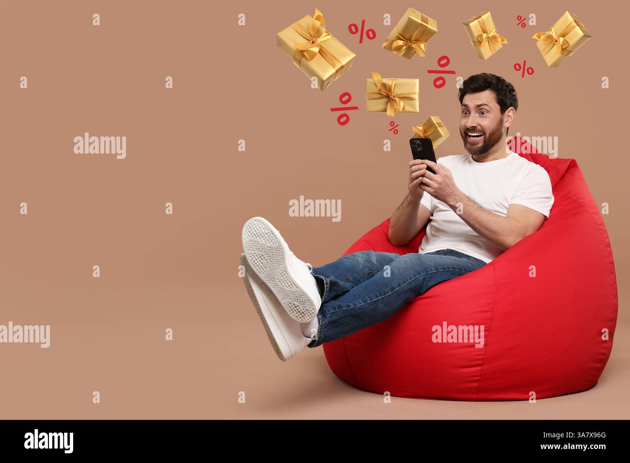 Bonus. Surprised man using mobile phone on pale brown background. Gift ...