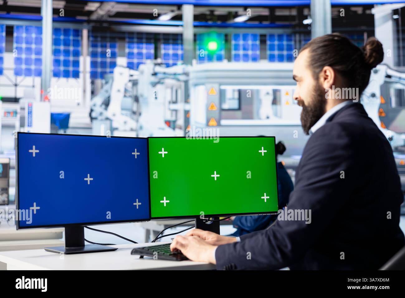 Man in solar panel plant adjusting robotic machinery settings through ...